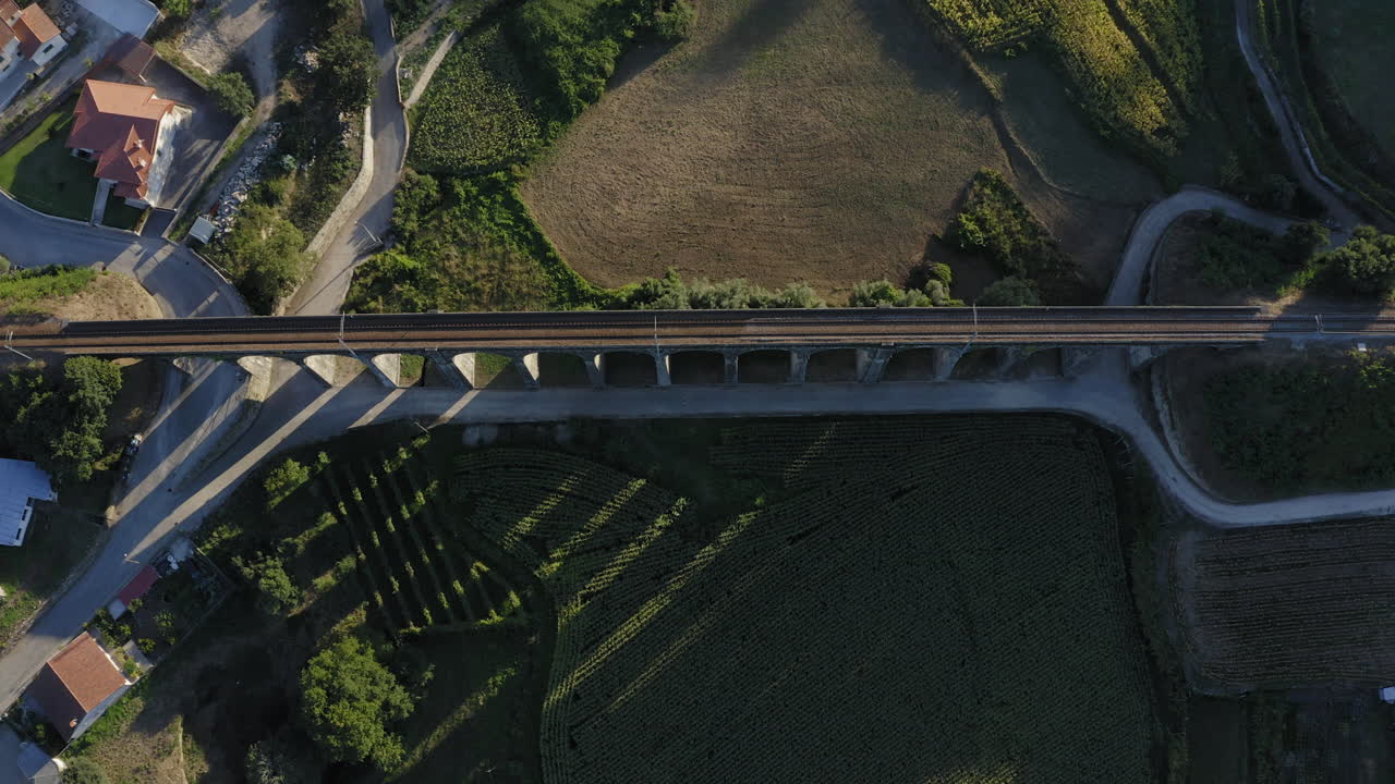 Crane down reveal shot of old arch railway bridge surrounded by crop ...