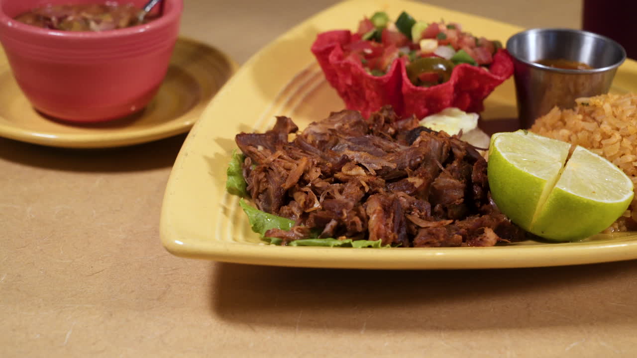 Premium stock video - Traditional pork carnitas plated with rice, pico ...