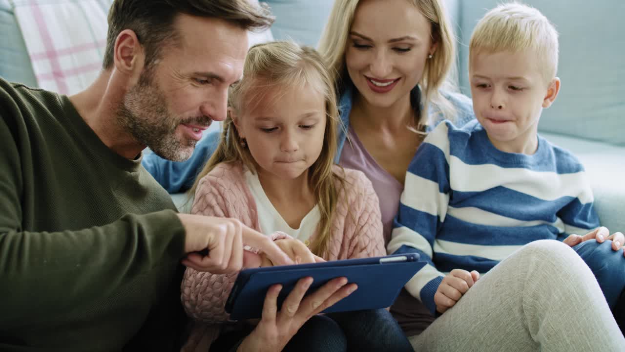 Premium stock video - Happy family using technology in living room