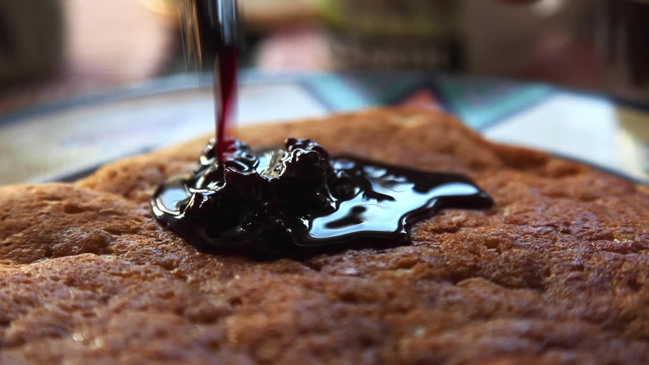 Premium stock video - Raspberry puree pouring on baked pancakes macro