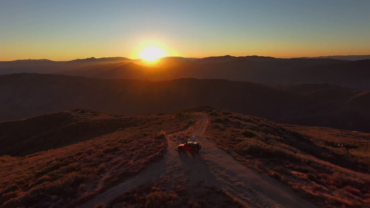 Man on top of overlanding jeep roof in middle of desert mountain at ...