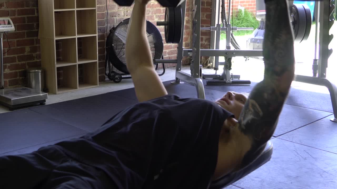 Muscly man in home gym exercising dumbbell press on bench | Premium ...