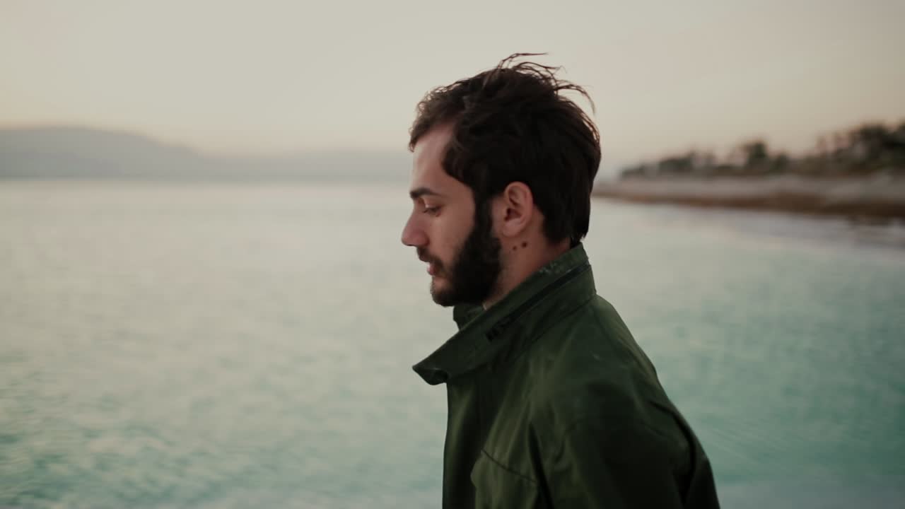 Profile view of grieving bearded man walking on edge of dead sea ...