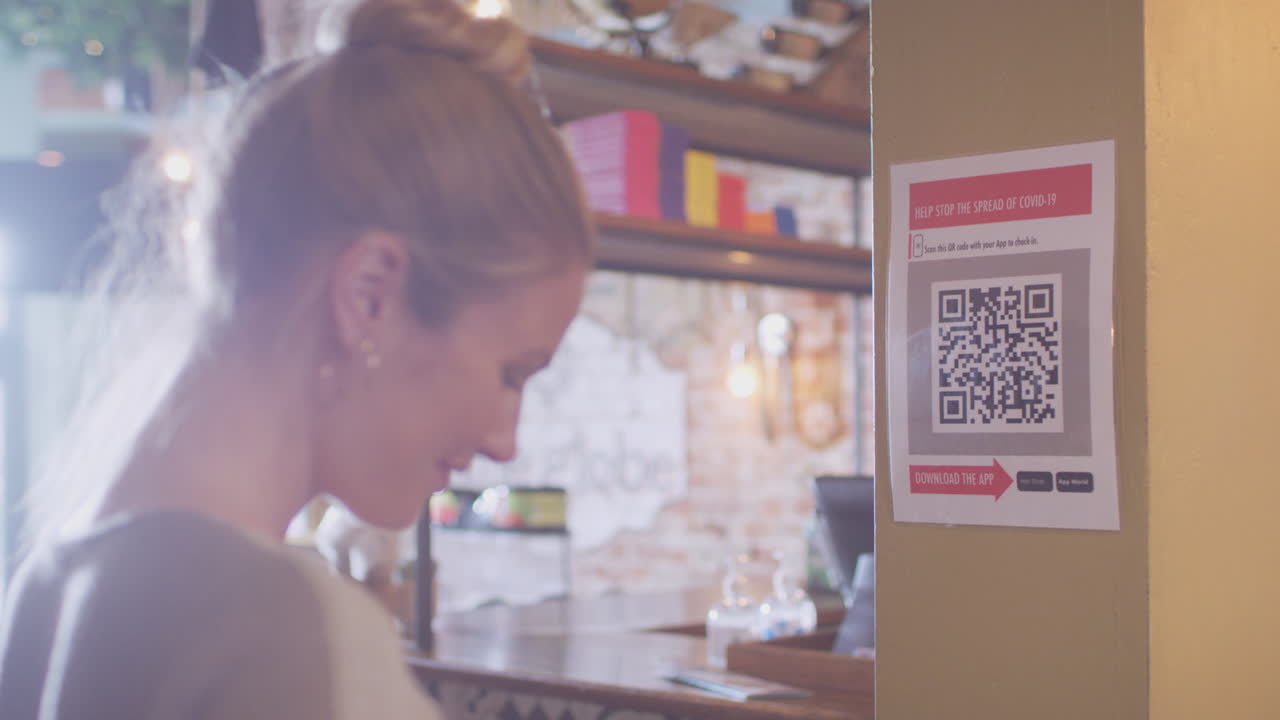 Woman with mobile phone checking into venue scanning qr code during ...