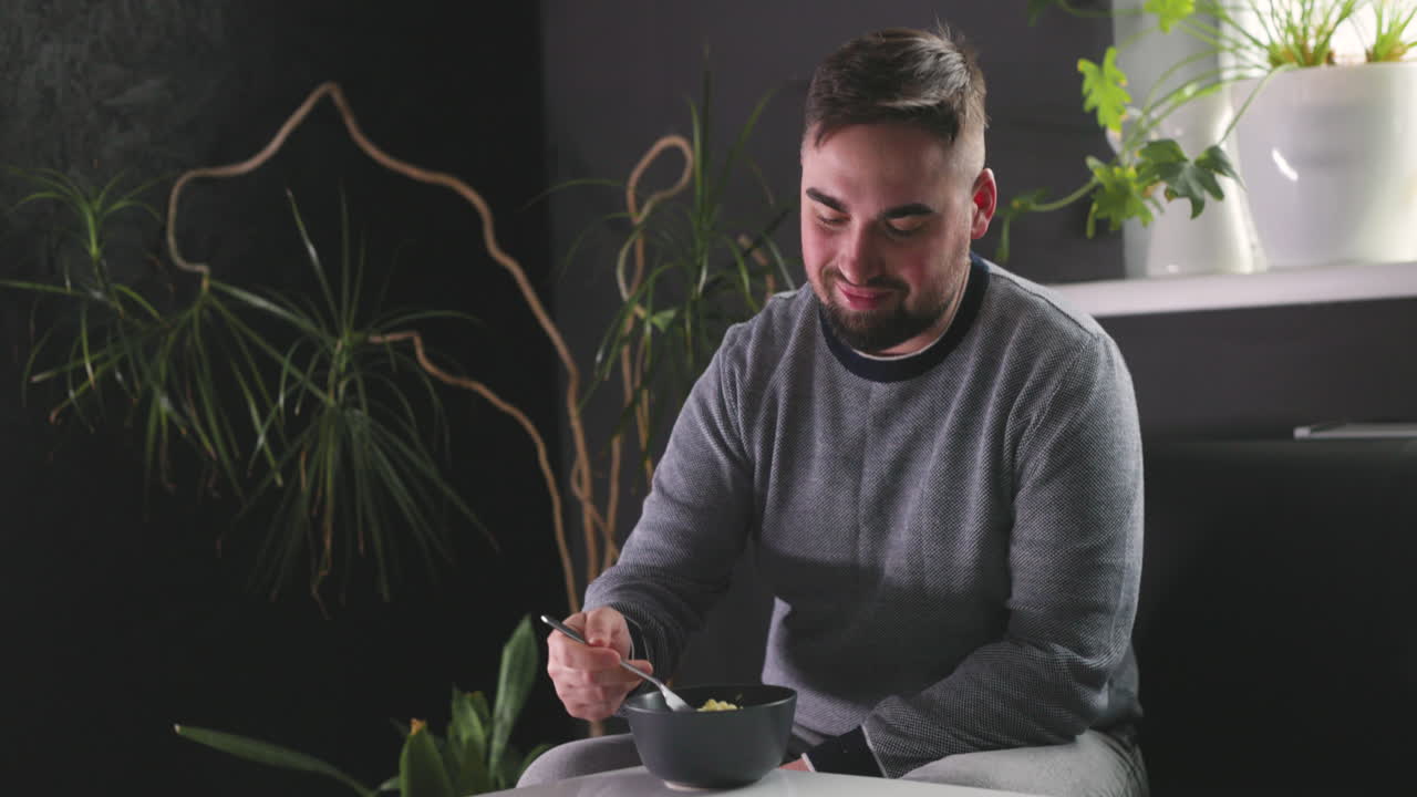 Free stock video - Hungry man sitting on sofa and eating delicious noodles