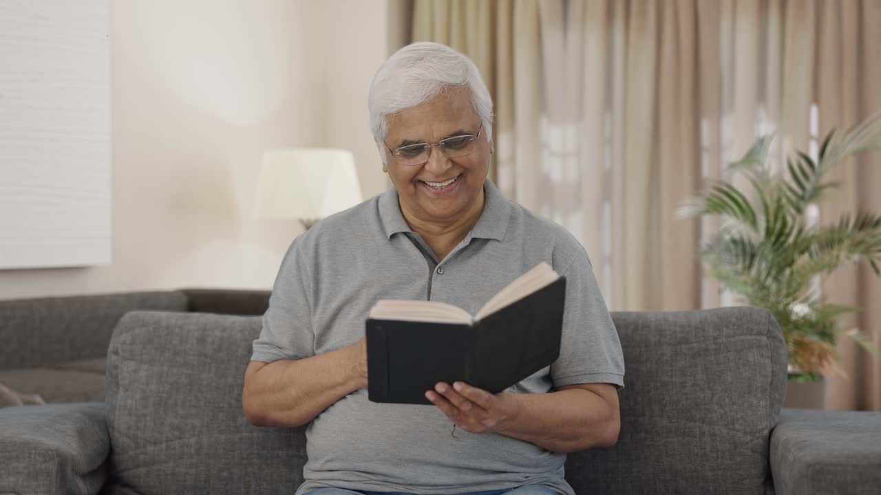 Happy indian old man reading book in morning Premium Stock Video Footage