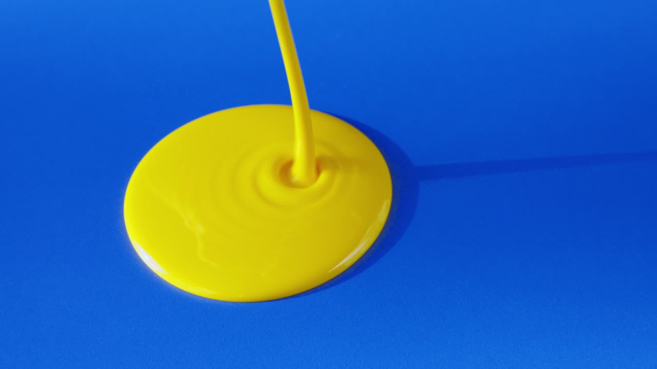Yellow Paint Dropping on a Blue Surface | Premium Stock Video Footage