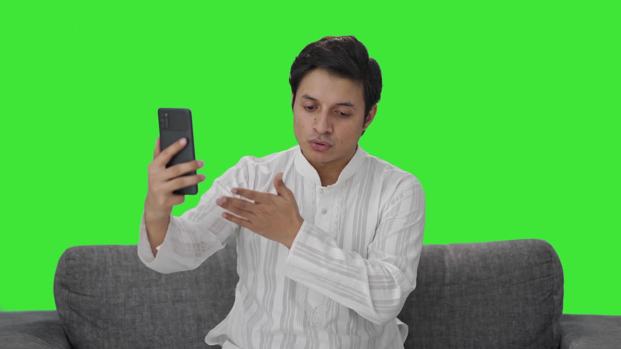 Premium stock video - Indian man talking on video call green screen