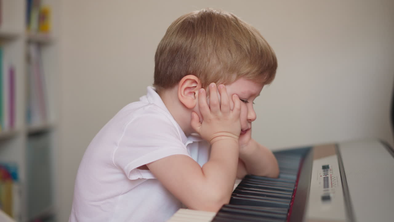 Premium stock video - Little boy stops playing piano and puts elbows on ...