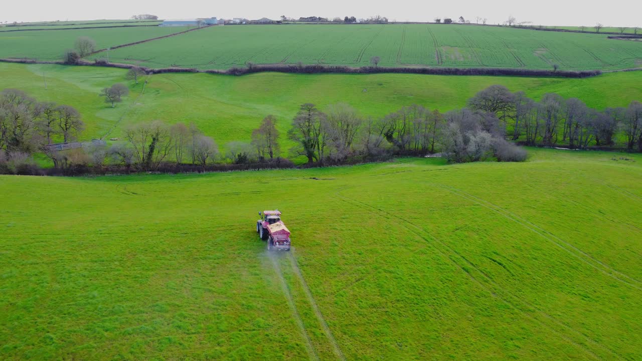 Smooth Aerial Drone View Following A Red Tractor Fertilising A Greet ...