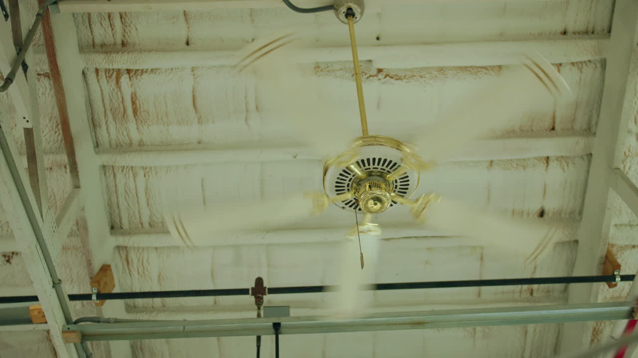 Ceiling fan spinning in industrial with exposed pipes and beams ...