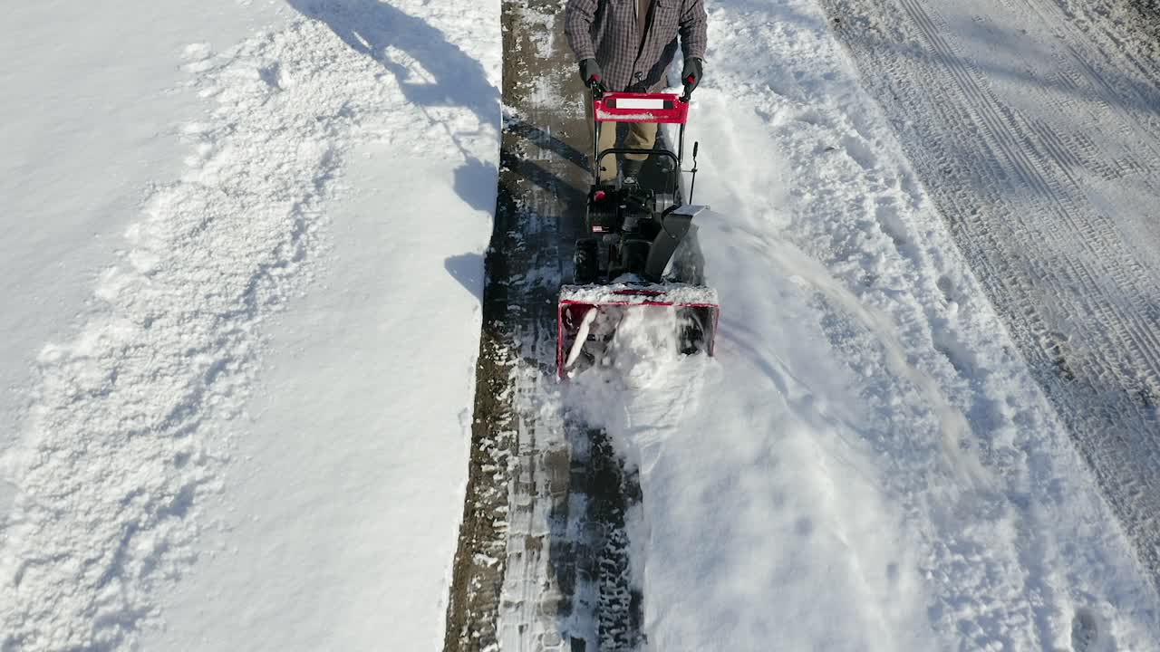 Camera pans up to show man using snow blower | Premium Stock Video Footage