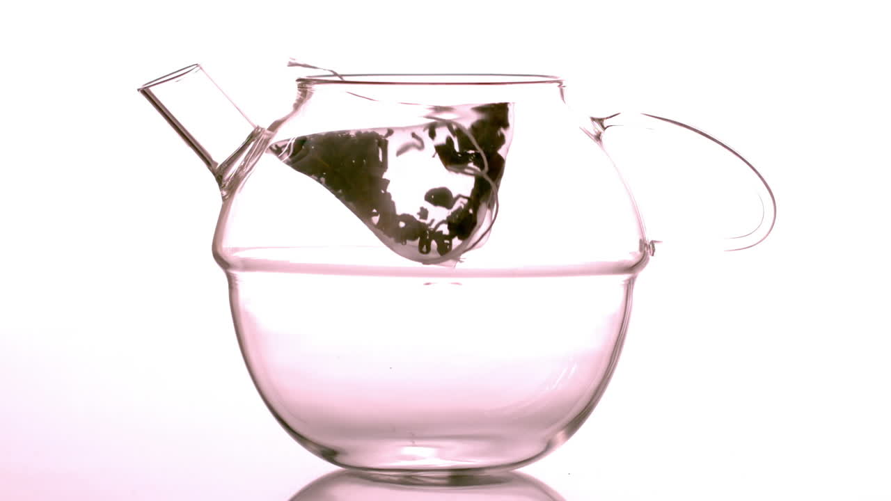 Premium stock video - Teabag falling into glass teapot