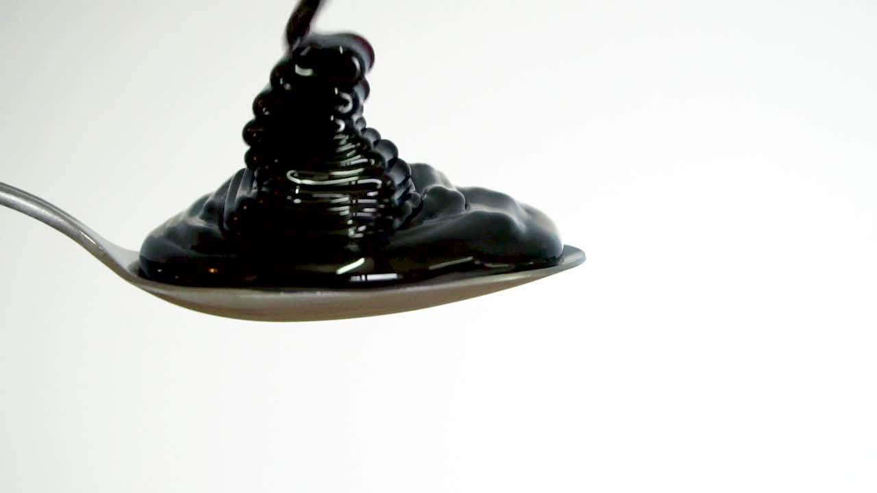 Molasses fills spoon and overflows, slow motion close up Premium Stock ...