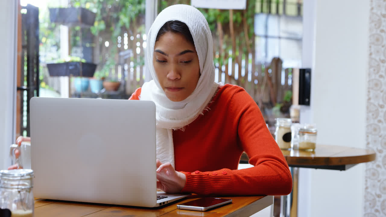 Woman having coffee while using laptop and mobile phone 4k Premium ...
