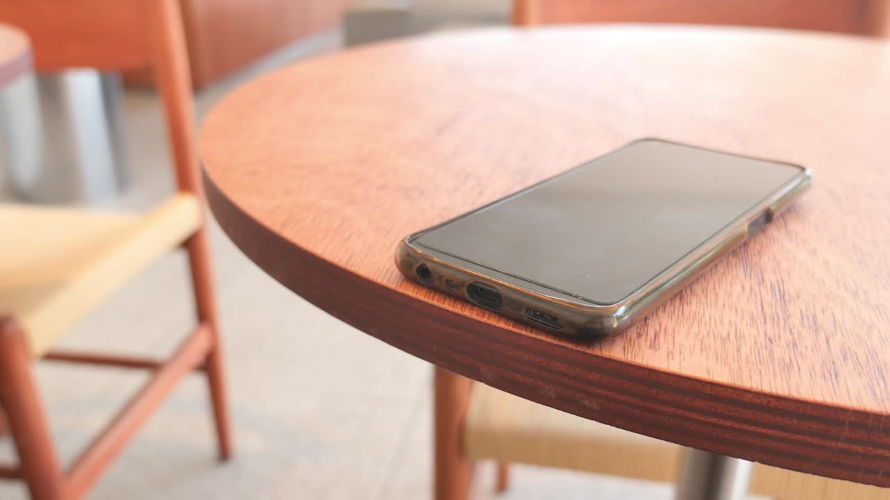 A cell phone lying on a wooden table in a cafe Premium Stock Video Footage
