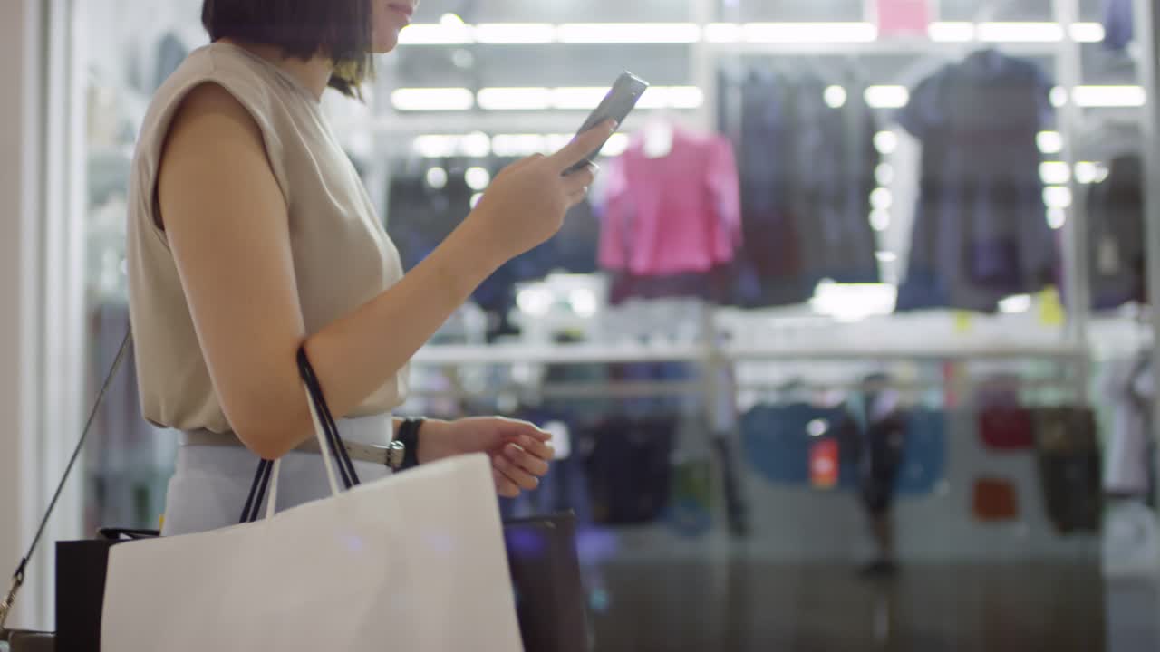 Close Up Of An Girl Walking While Holding Shopping Bags And Using Her ...