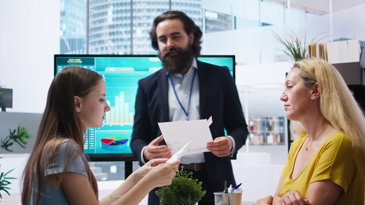 Financial advisor showing statistical graphs on big screen to customers ...