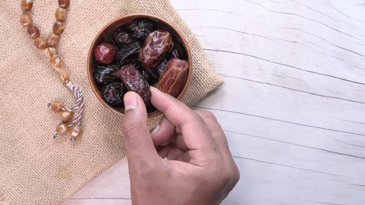 The concept of ramadan, hand pick date fruit from a bowl | Premium ...
