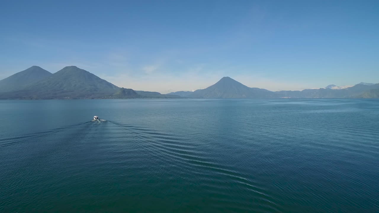 Aerial over a boat on lake amatitlan in guatemala reveals the pacaya ...