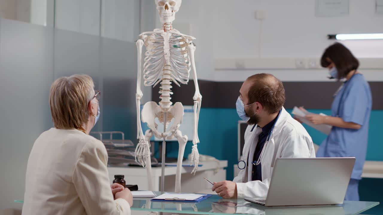 Physician pointing at human skeleton to explain osteopathy diagnosis ...