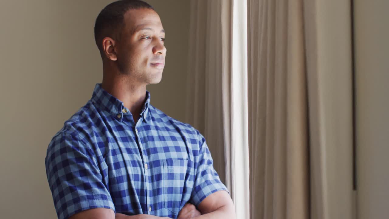 Premium stock video - Thoughtful biracial man standing at window and ...