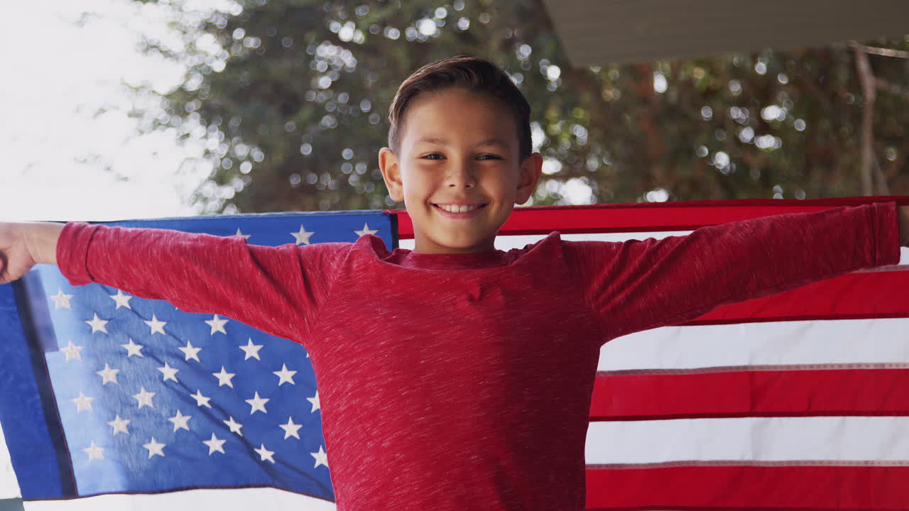 Portrait of proud hispanic boy wrapped in stars and stripes american ...