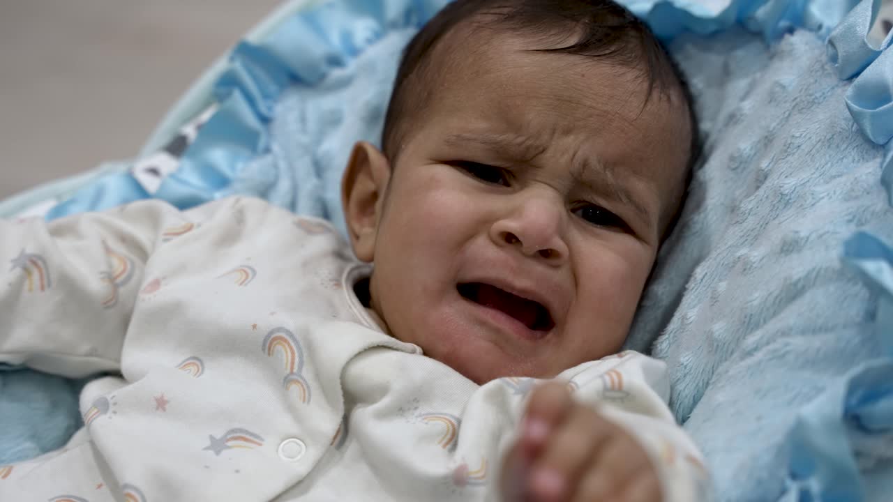 Distressed six month old asian indian baby expresses attention with ...