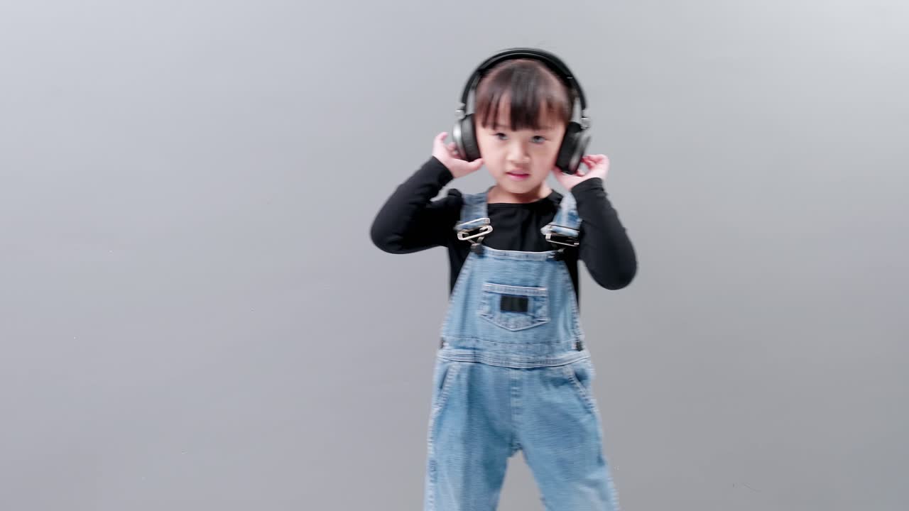 Premium stock video - Child with overalls listening to music with headset