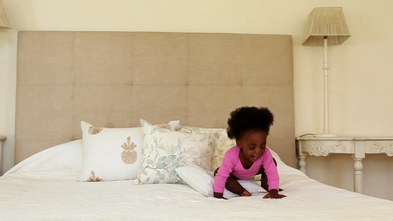 Premium stock video - Cute baby girl standing and clapping on bed