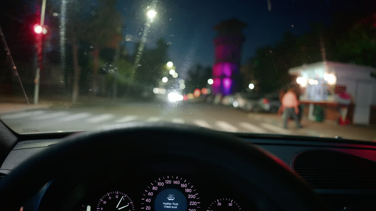 Blurred view of city intersection at night, seen through a car ...