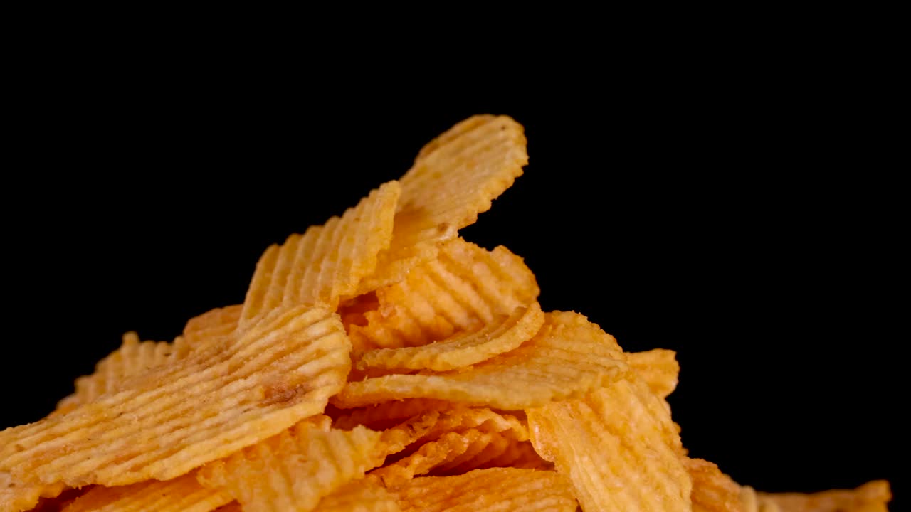 Golden ridged potato chips rotate smoothly under studio lighting ...