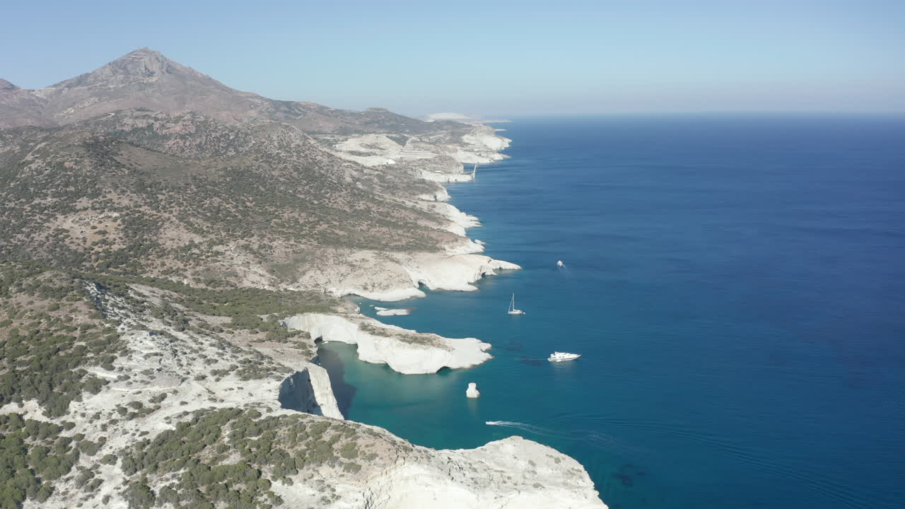 Aerial Wide Dolly Forward Of Shoreline With White Rocks And Boats In ...