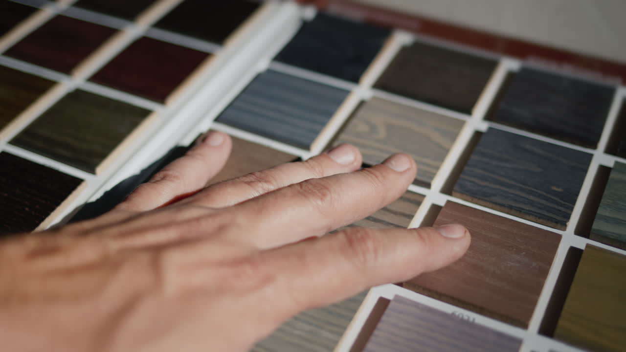 A man chooses a paint color, his hand runs over wooden samples. Repair ...