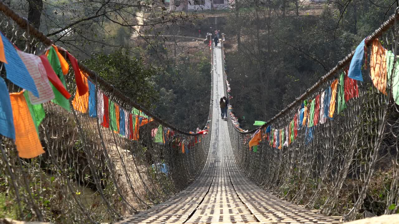Premium stock video - Prayer flags hanging from a swinging bridge over ...