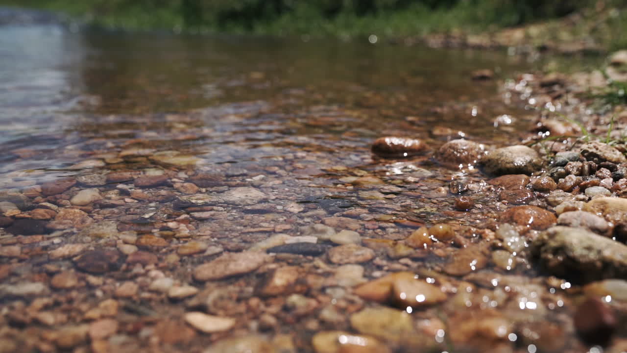 Premium stock video - Close up of water trickling over pebbles on a ...