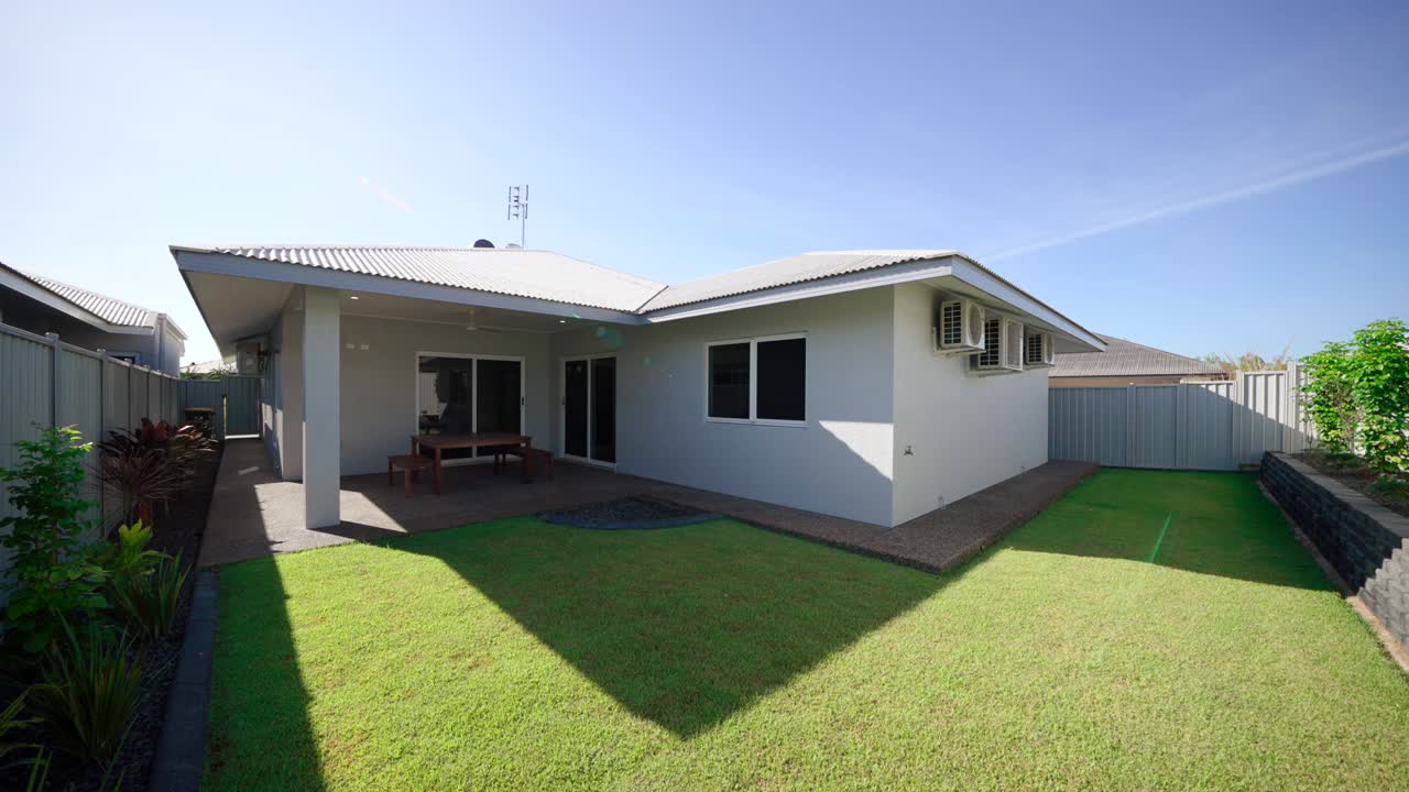 Modern display home backyard with a spacious lawn and surrounding ...
