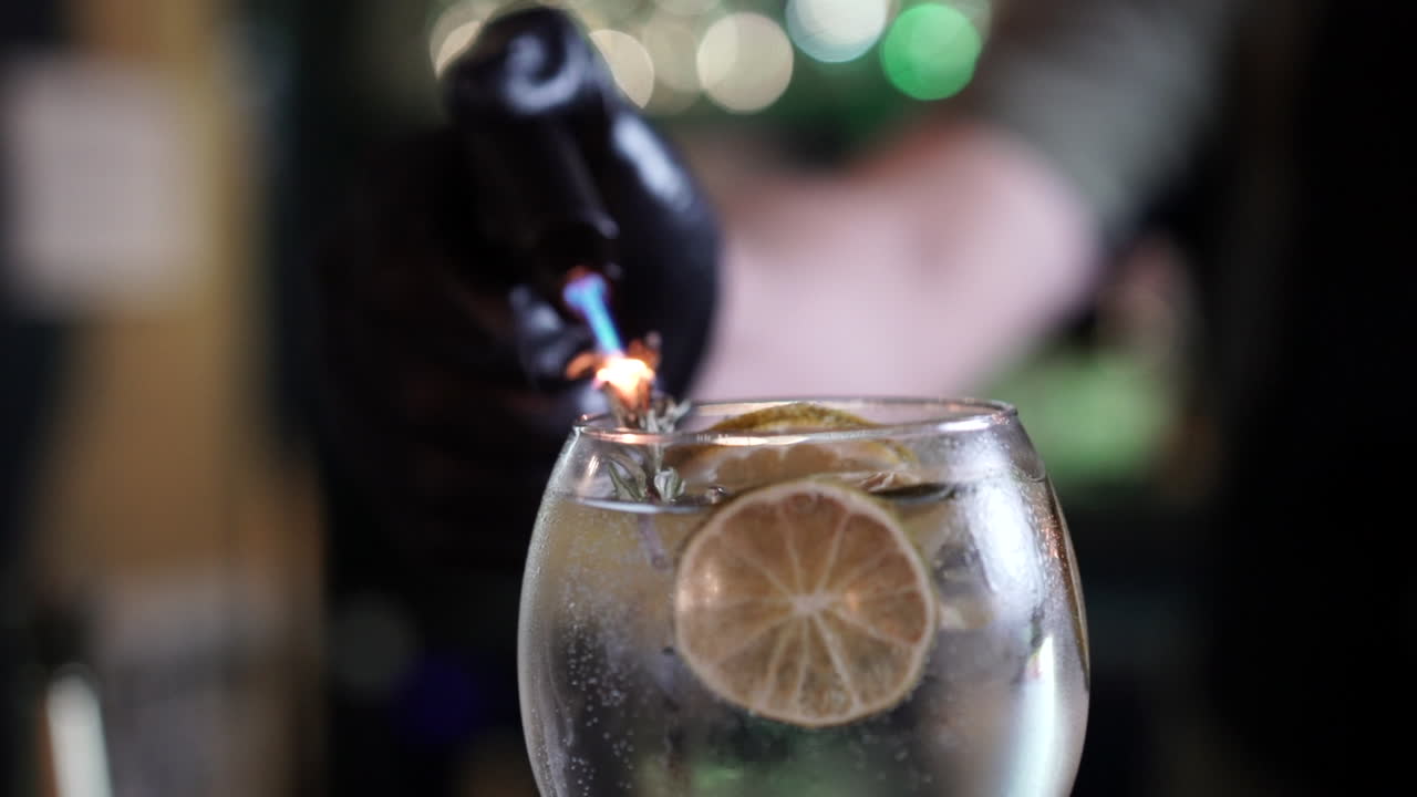 Premium stock video - Bartender mixologist smoking flaming rosemary garnish citrus vodka tonic ...