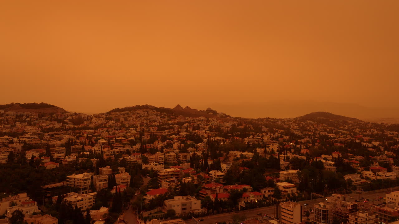 Drone pans over Athens under thick Sahara storm dust with dim glowing ...