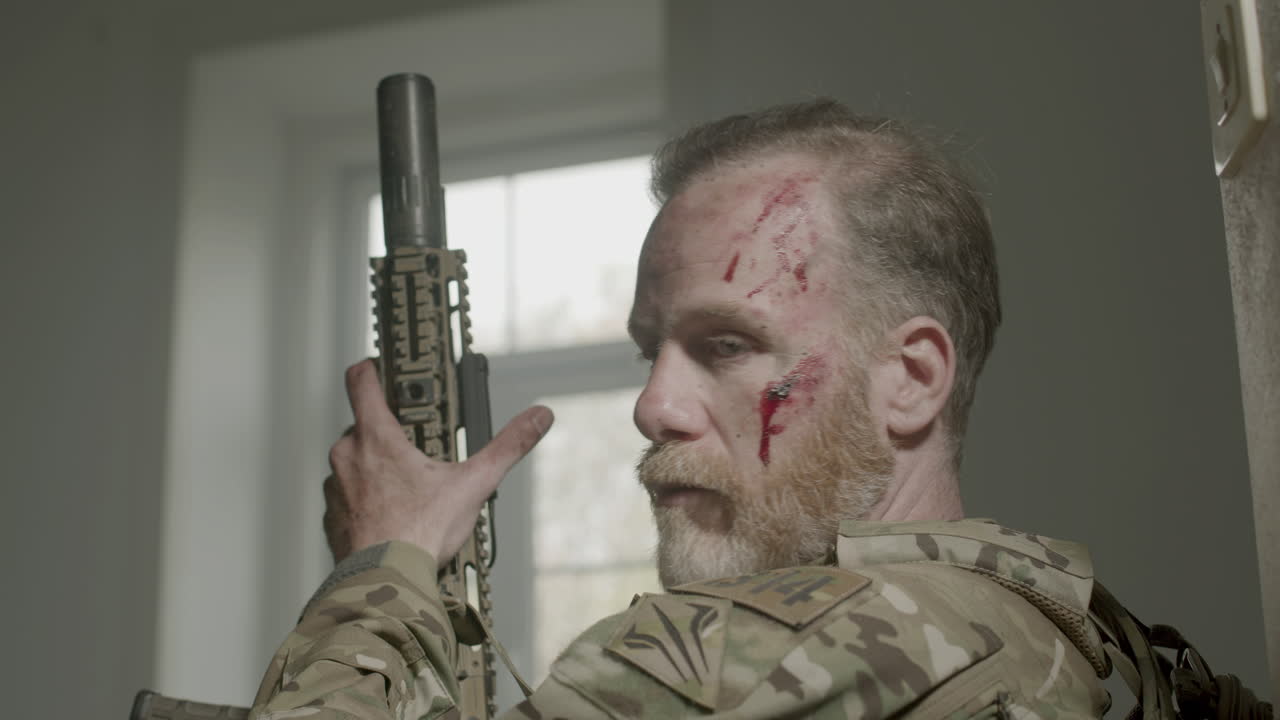 Free stock video - Serious soldier with blood on face taking sight
