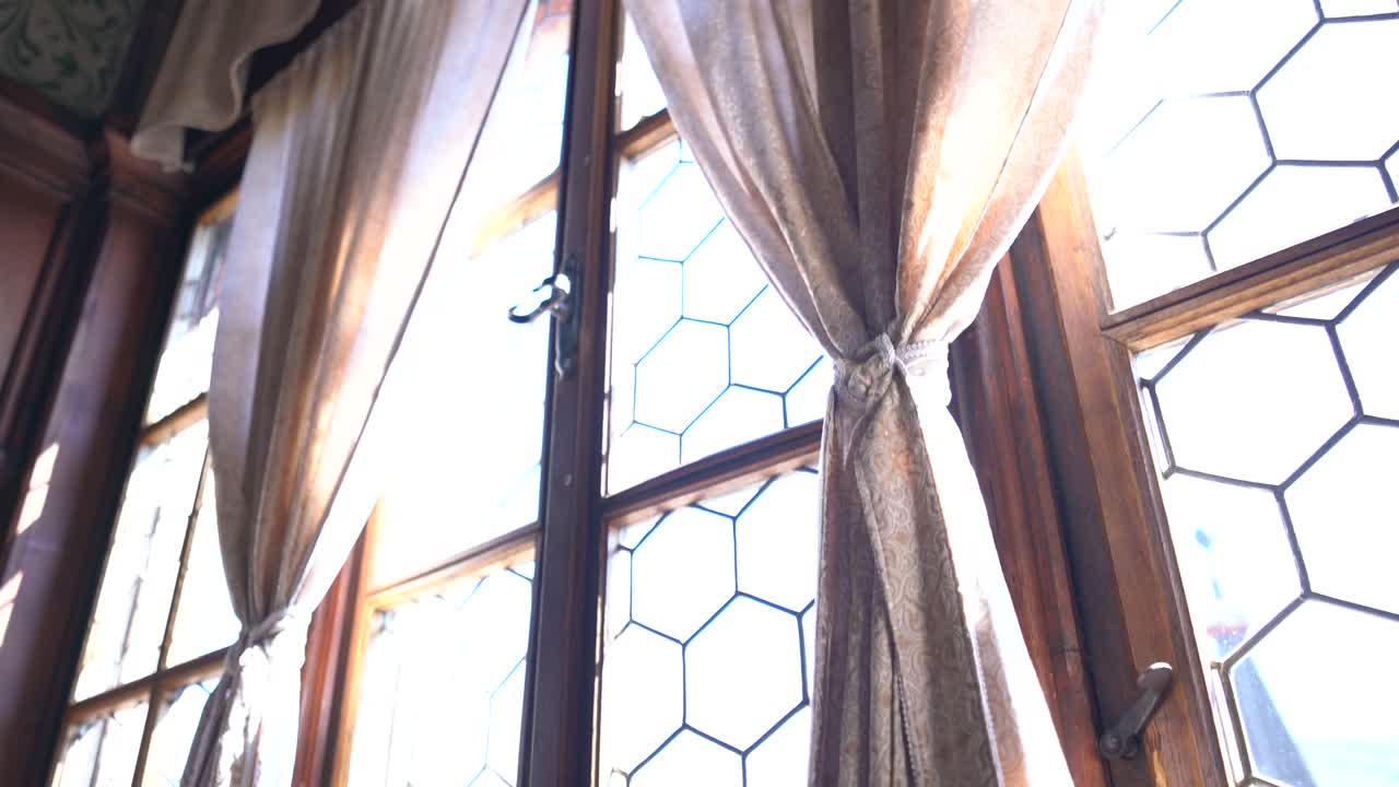 Premium stock video - A tilt up shot of an antique window and curtains