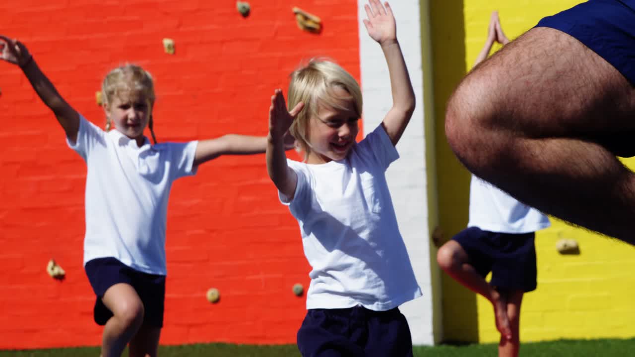 Yoga instructor instructing children in performing exercise Premium ...