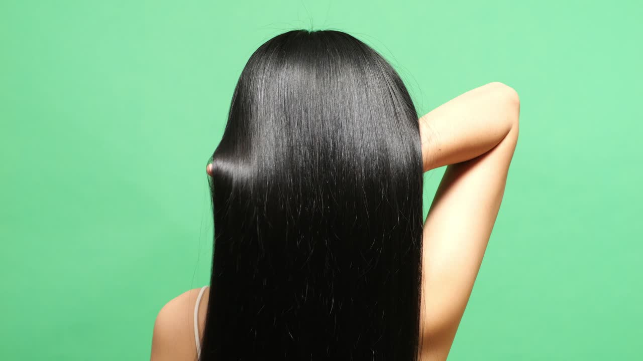 Close up back view of a woman gently touching her long and black ...