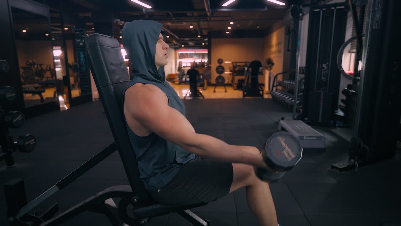 Side view of athletic man in 30s performing front dumbbell raise ...