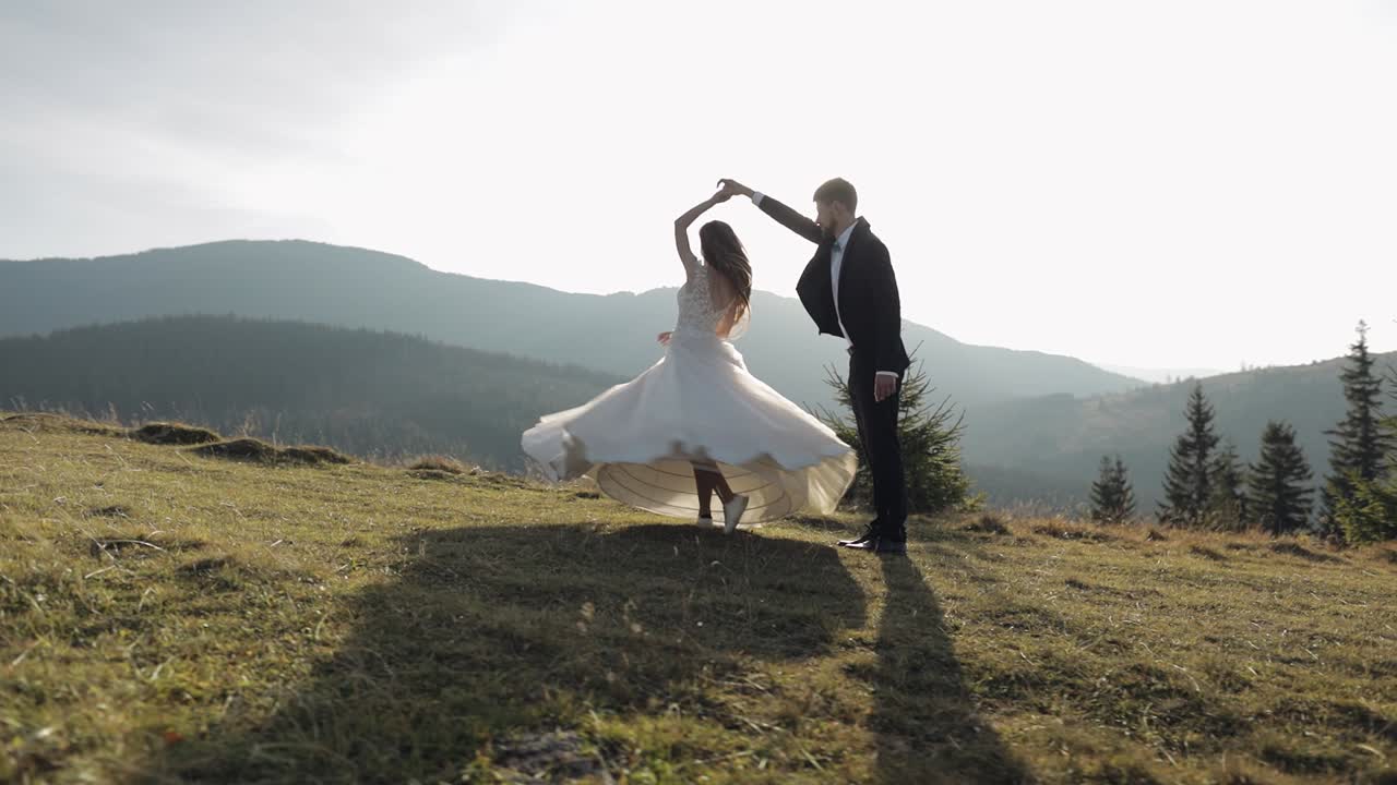 Newlyweds. Caucasian groom with bride dancing on mountain slope ...