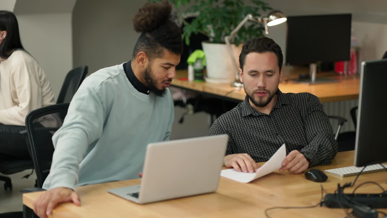 Premium stock video - Two male colleagues employees cooperating in ...