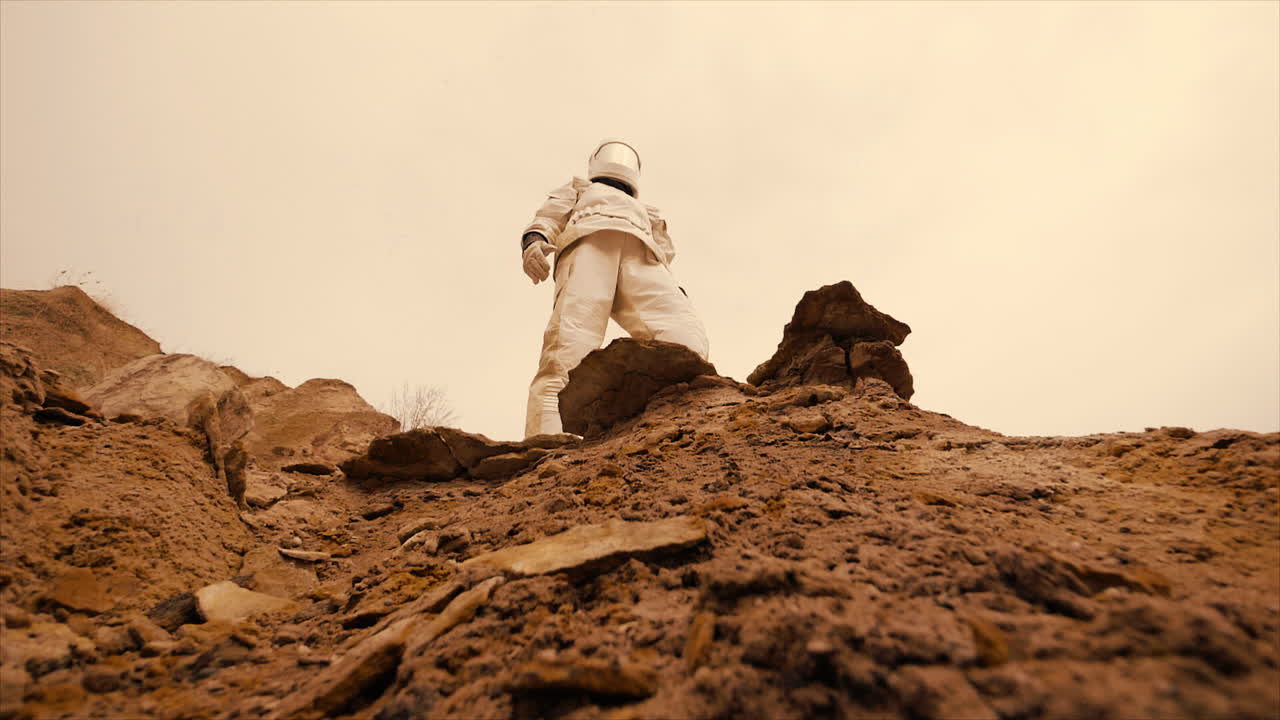 Premium stock video - An astronaut wearing a spacesuit, moving across a ...