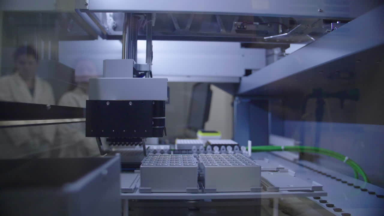 Free stock video - Automated pipetting system in action in a laboratory with scientist in back