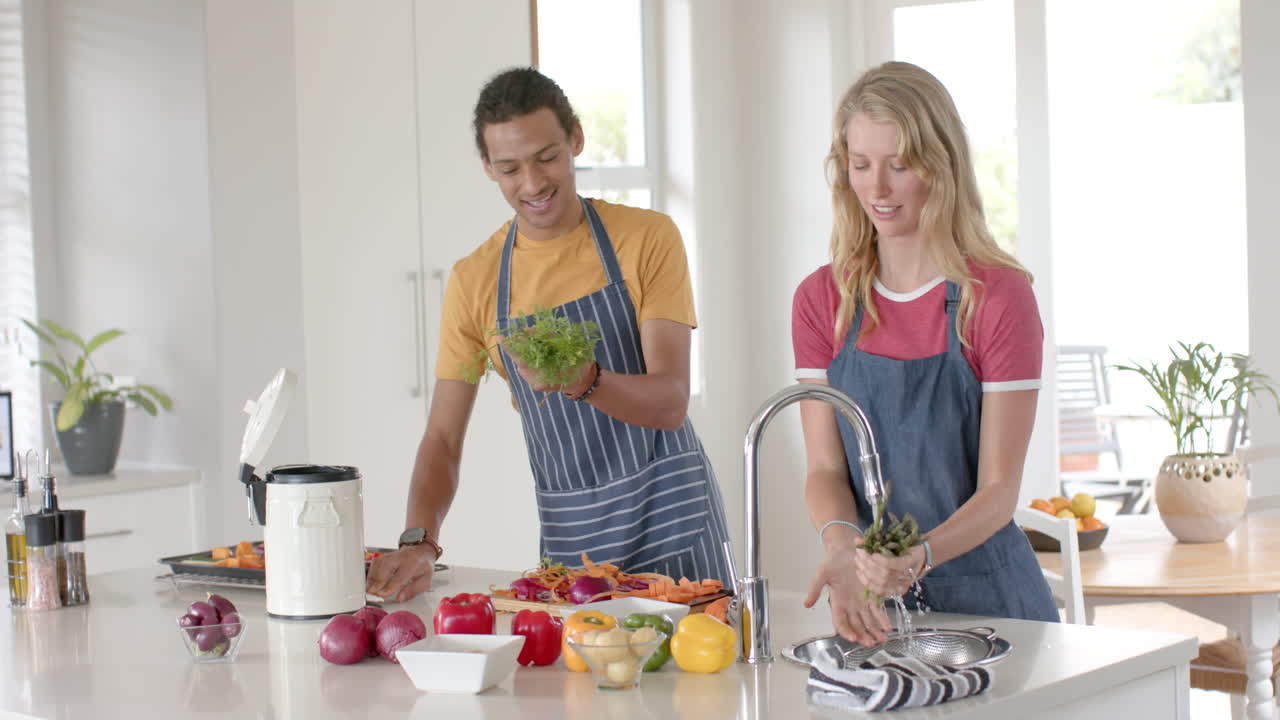 Happy diverse couple cooking and throwing waste out in kitchen, slow ...