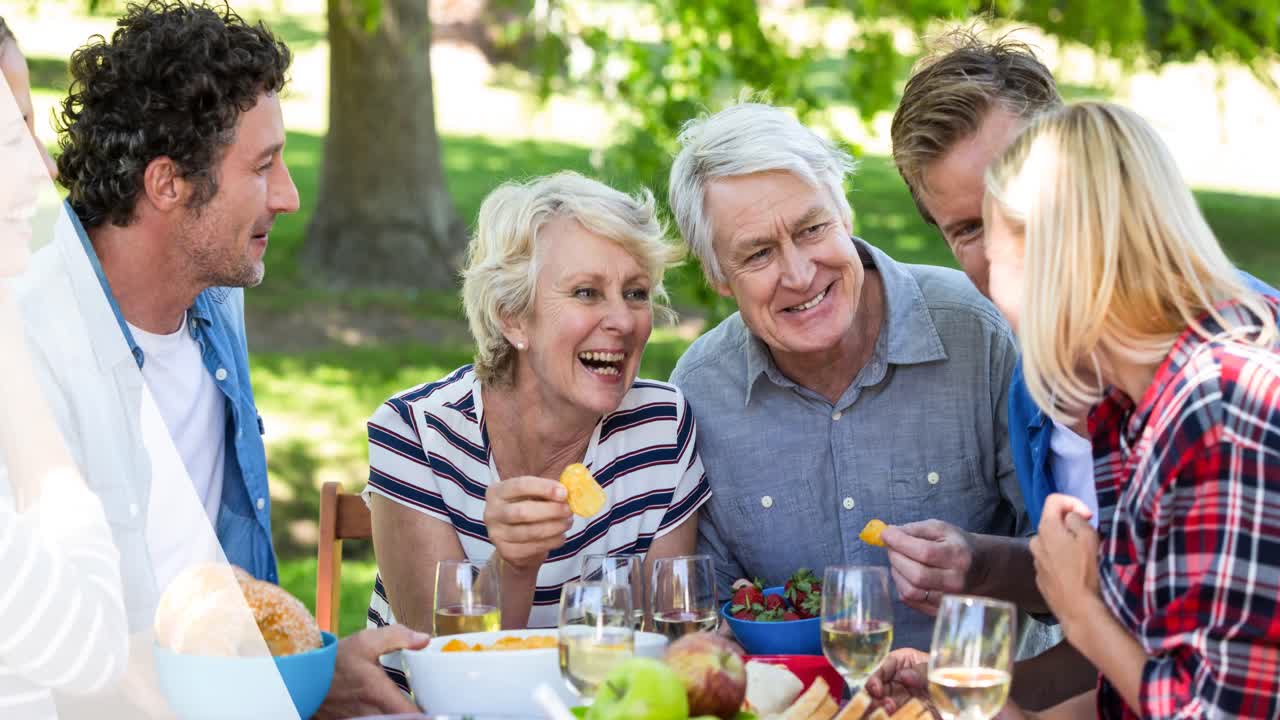 Animation of picnic basket over happy caucasian family having picnic in ...